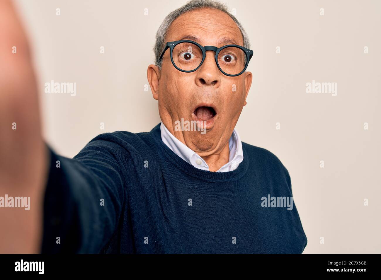 Senior handsome grey-haired man wearing sweater and glasses making ...