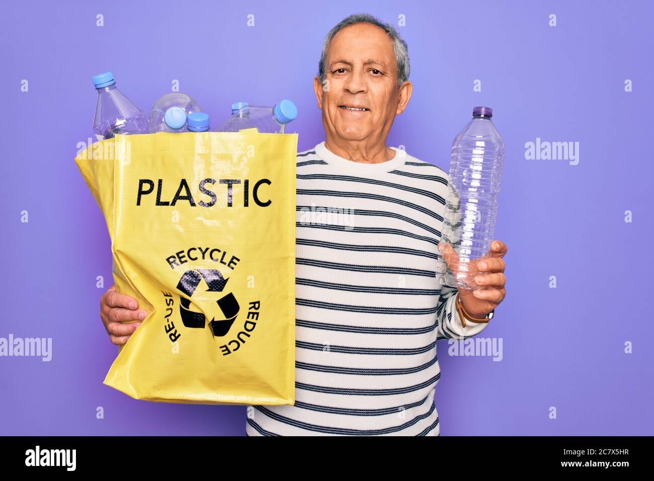 Senior man recycling holding bag with plastic bottles to recycle over ...
