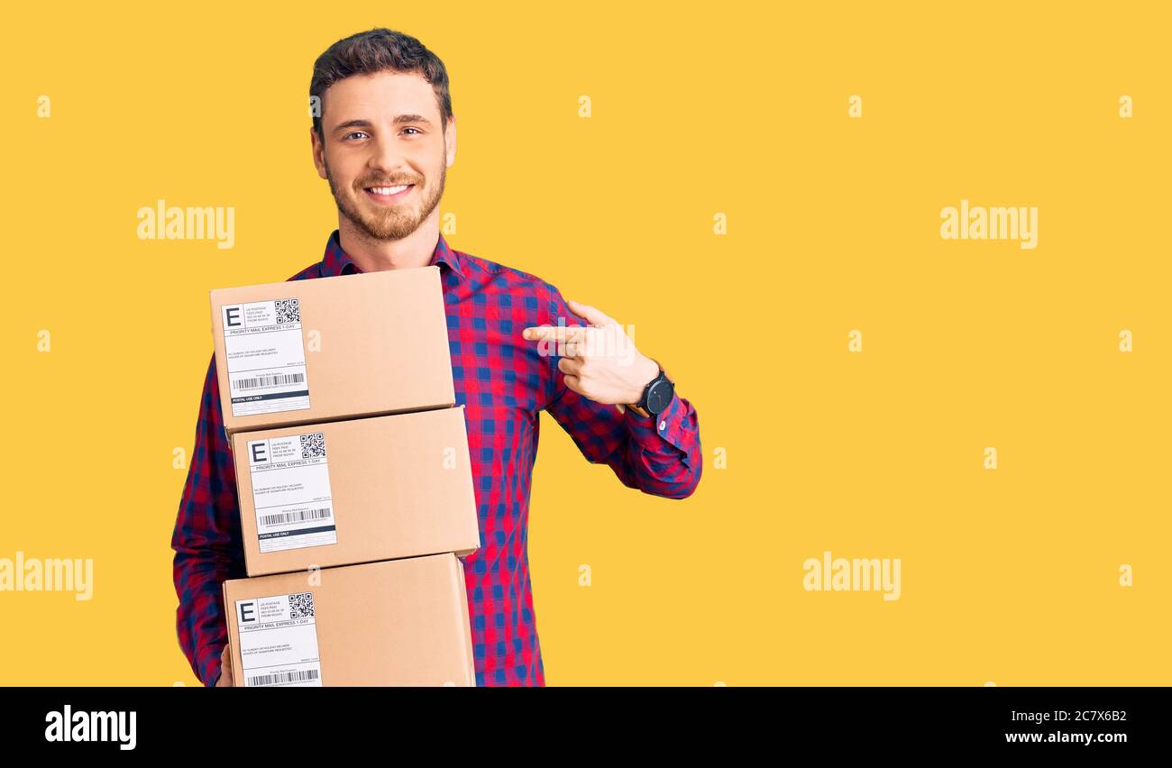 Handsome young man with bear holding delivery packages pointing finger ...