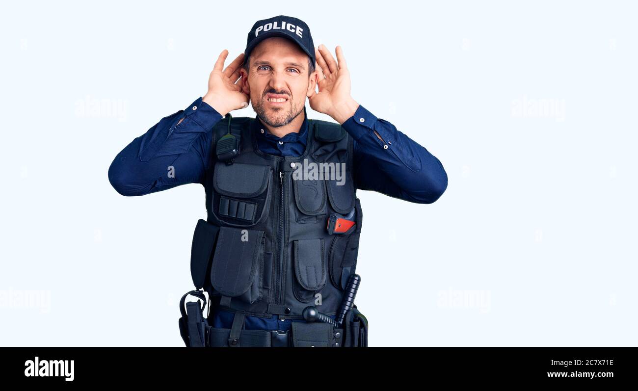 Young handsome man wearing police uniform trying to hear both hands on ...