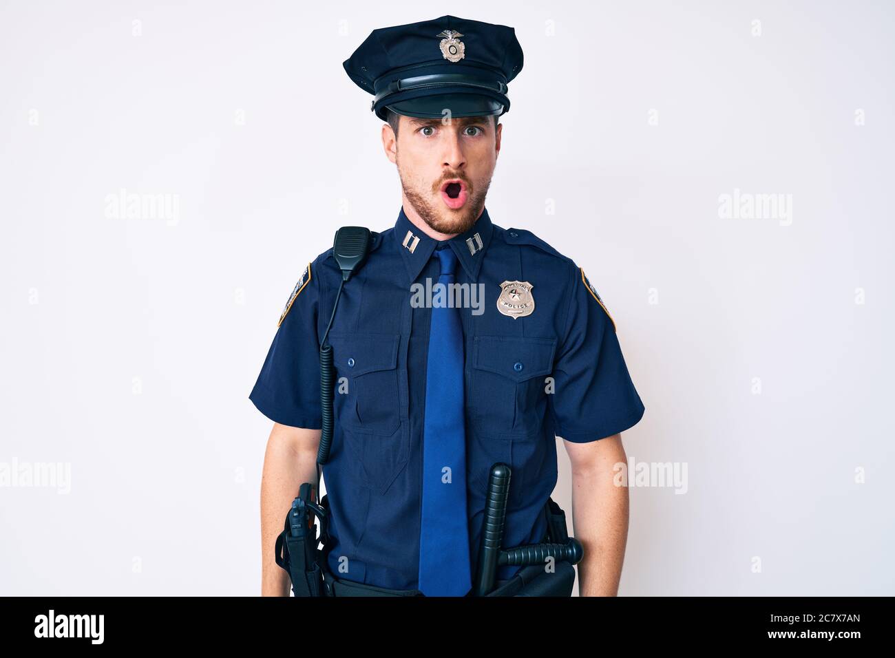 Young caucasian man wearing police uniform in shock face, looking ...