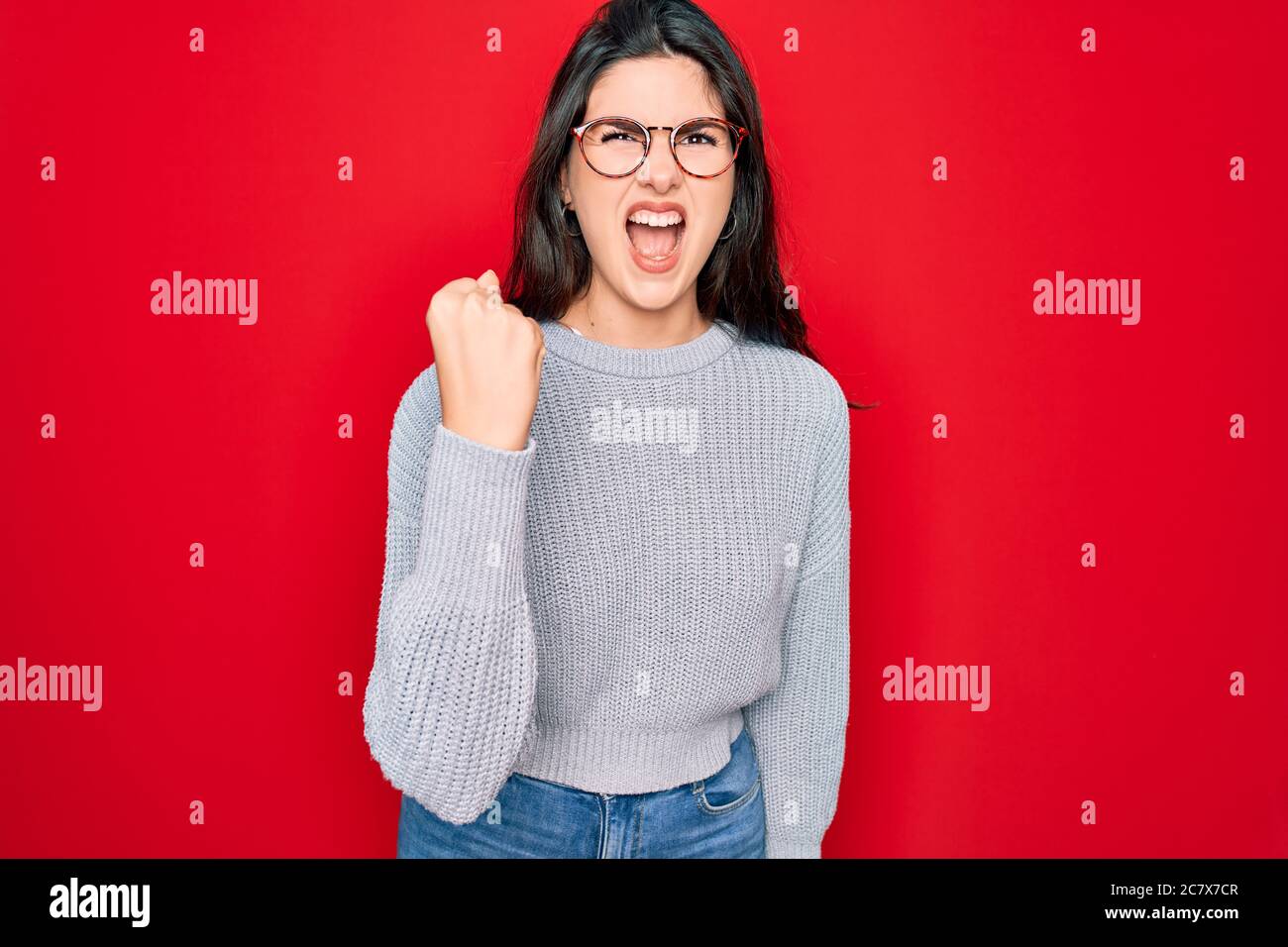 Young beautiful brunette woman wearing casual sweater over red ...