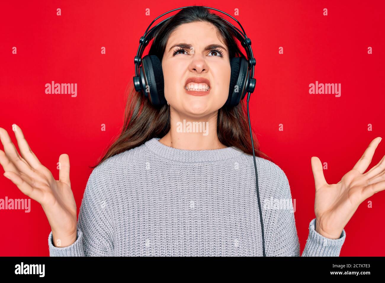 Young beautiful girl wearing modern headphones listening to music over ...