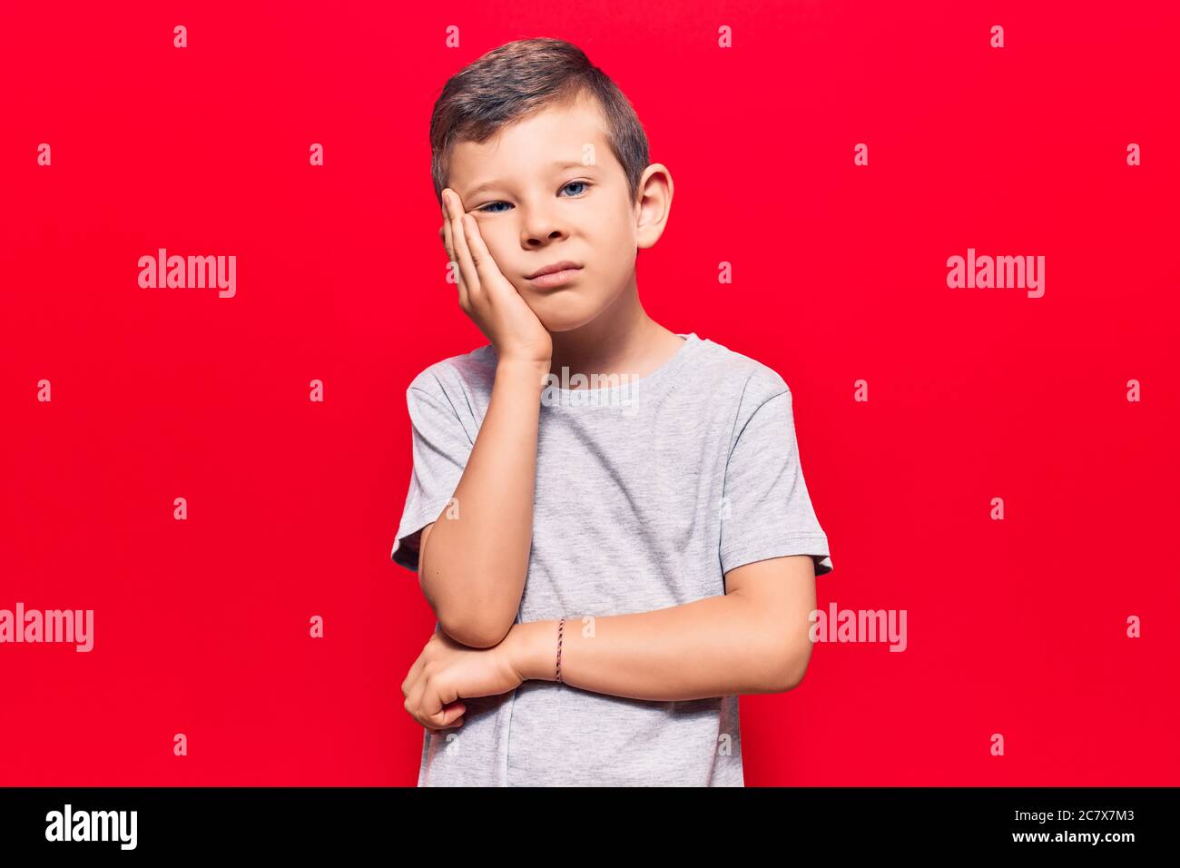 Cute blond kid wearing casual clothes thinking looking tired and bored ...