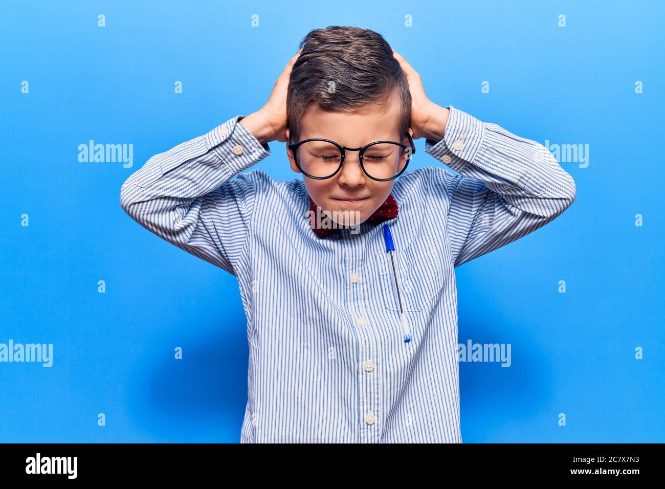 Cute blond kid wearing nerd bow tie and glasses suffering from headache ...