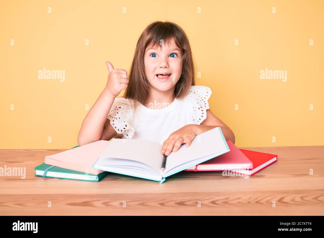 Little caucasian kid girl with long hair studying for school exam ...