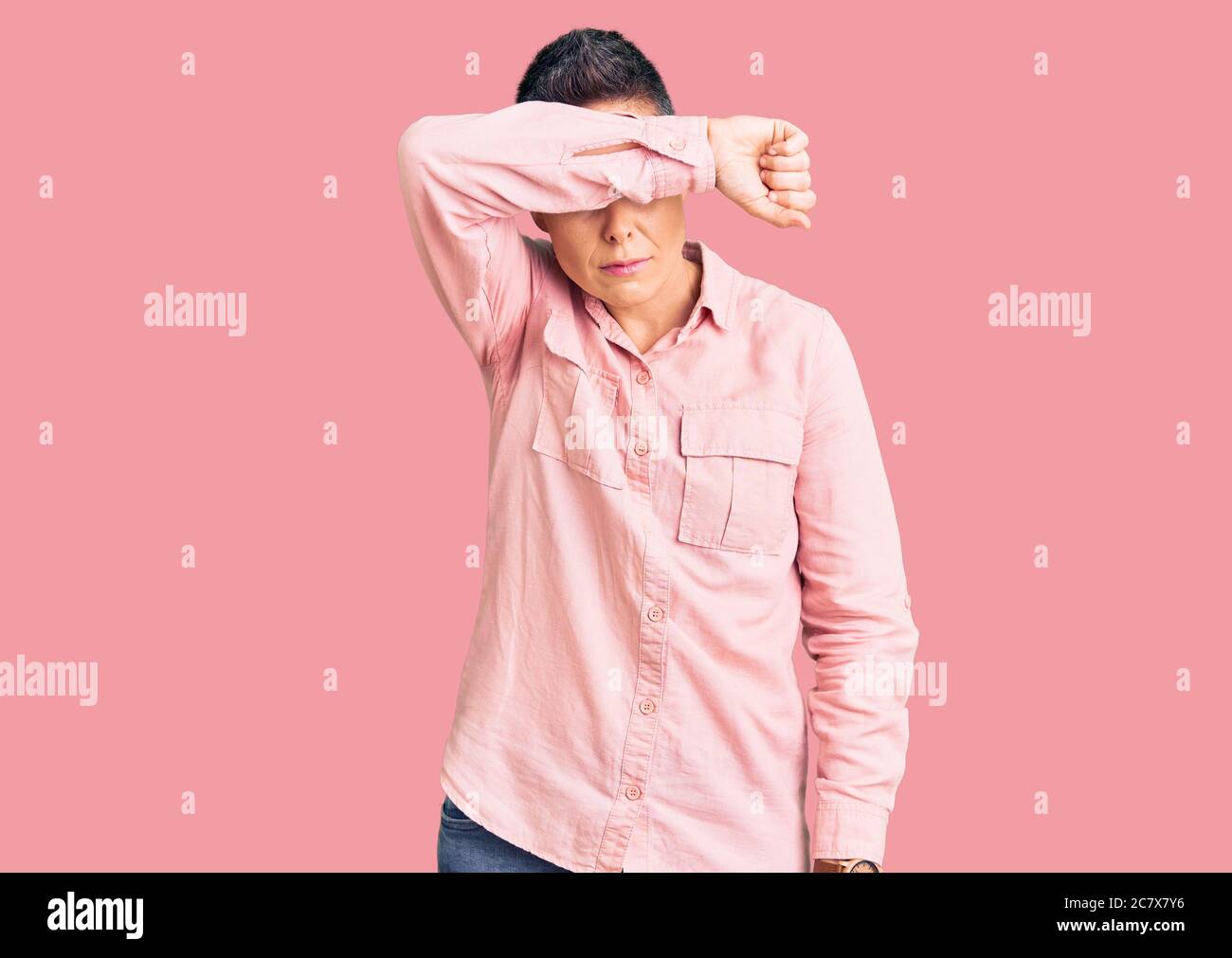 Young woman with short hair wearing casual clothes covering eyes with ...