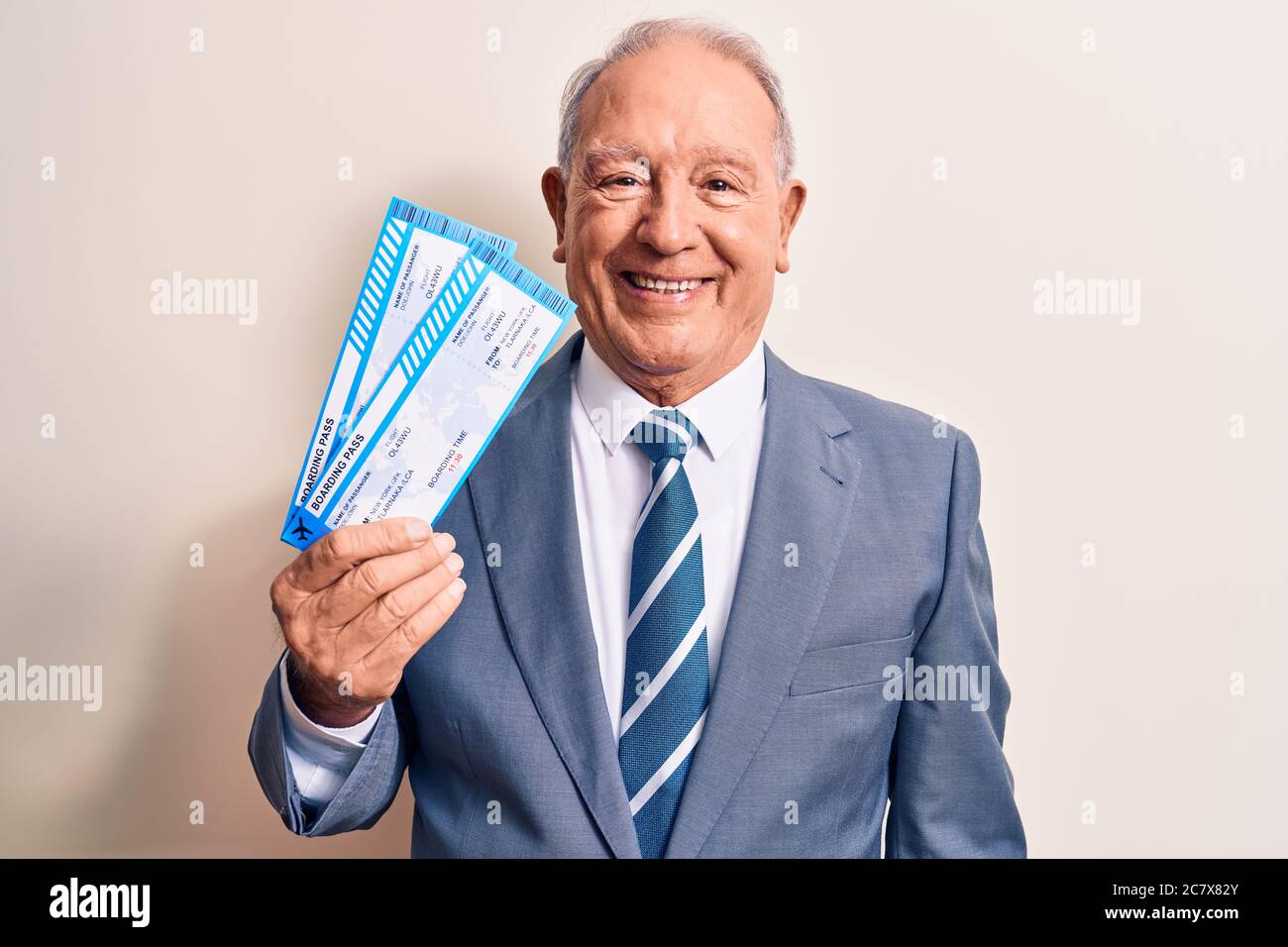 Handsome grey-haired man wearing suit holding airline boarding pass ...
