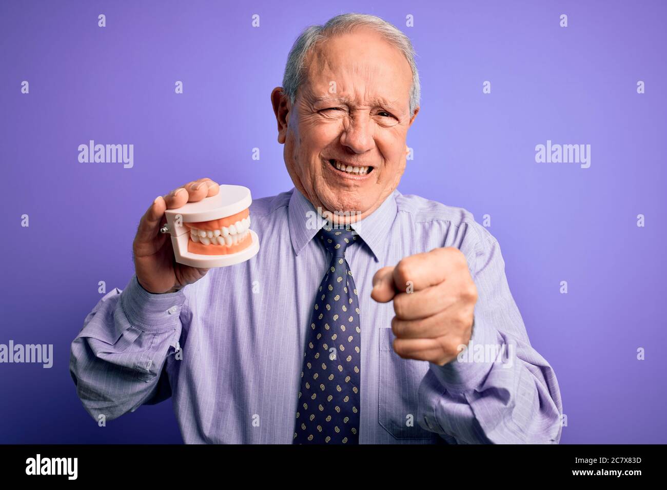 Grey haired senior man holding orthodontic prosthesis denture over ...