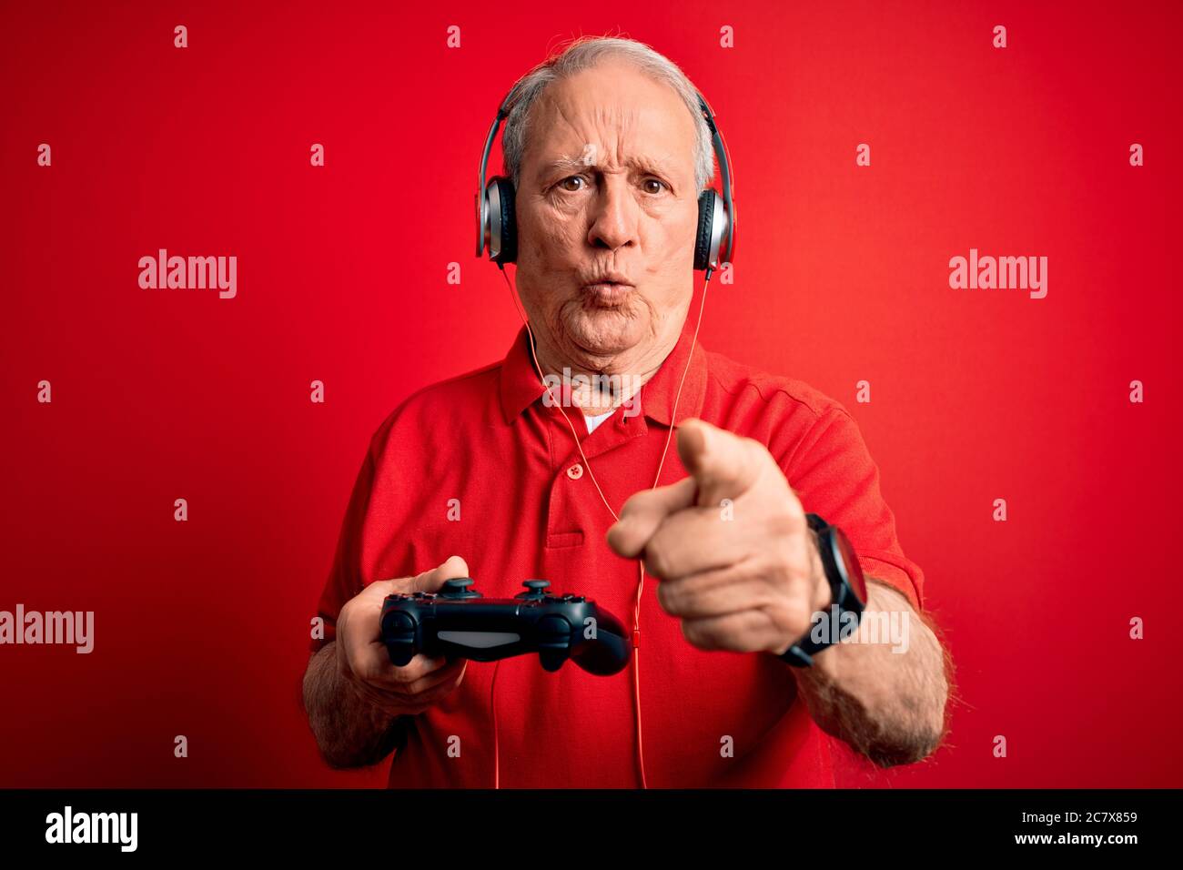Senior grey haired gamer man playing video games using gamepad joystick ...