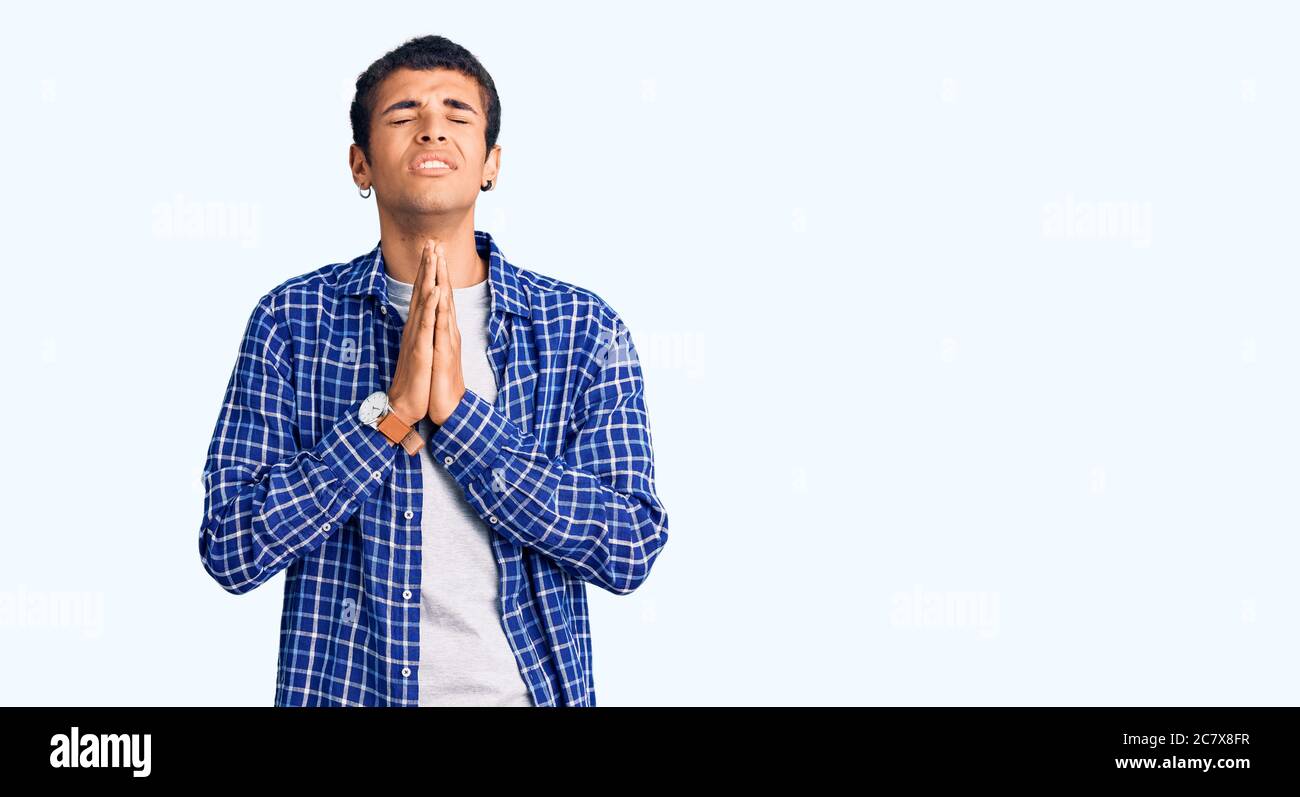 Young african amercian man wearing casual clothes begging and praying ...