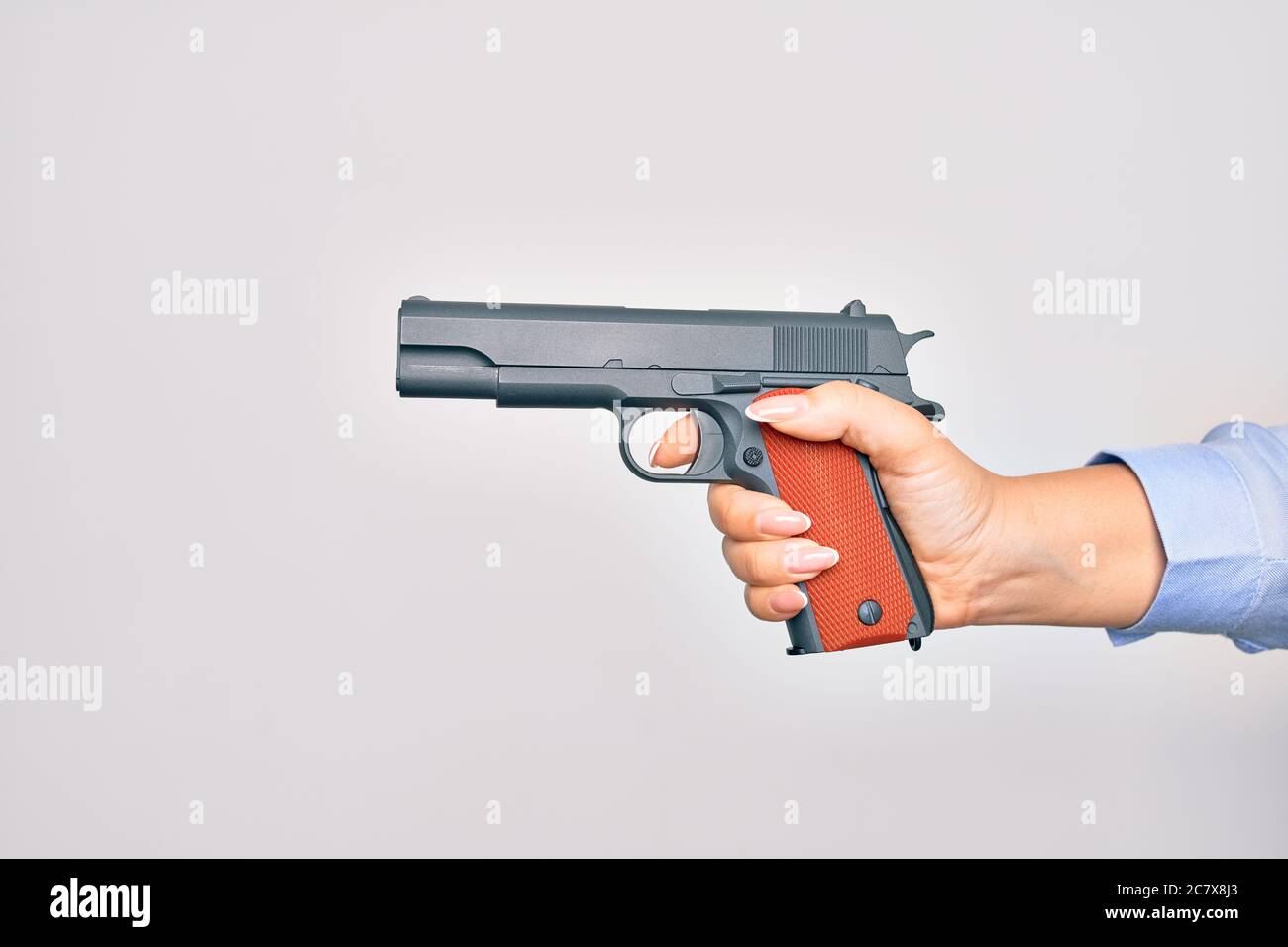 Hand of caucasian young woman holding gun over isolated white ...