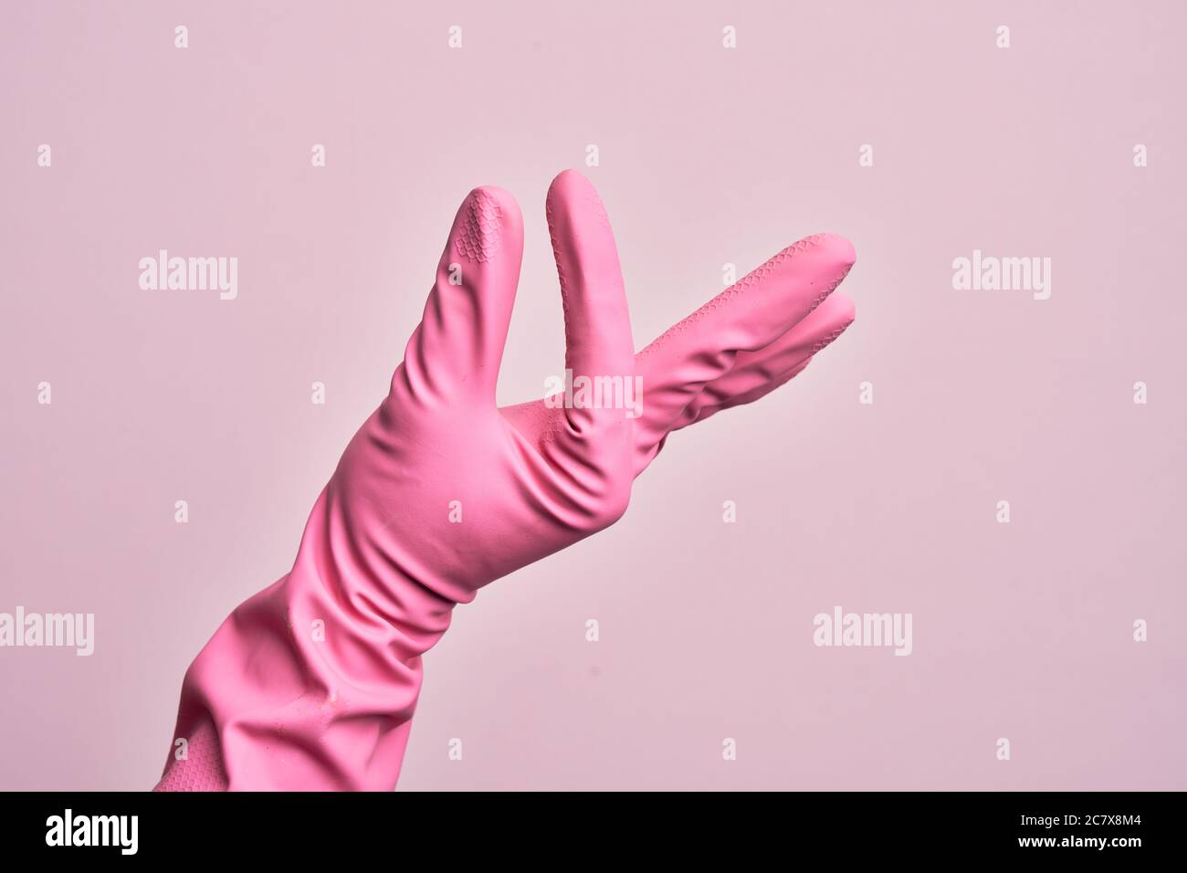 Hand of caucasian young man with cleaning glove over isolated pink ...
