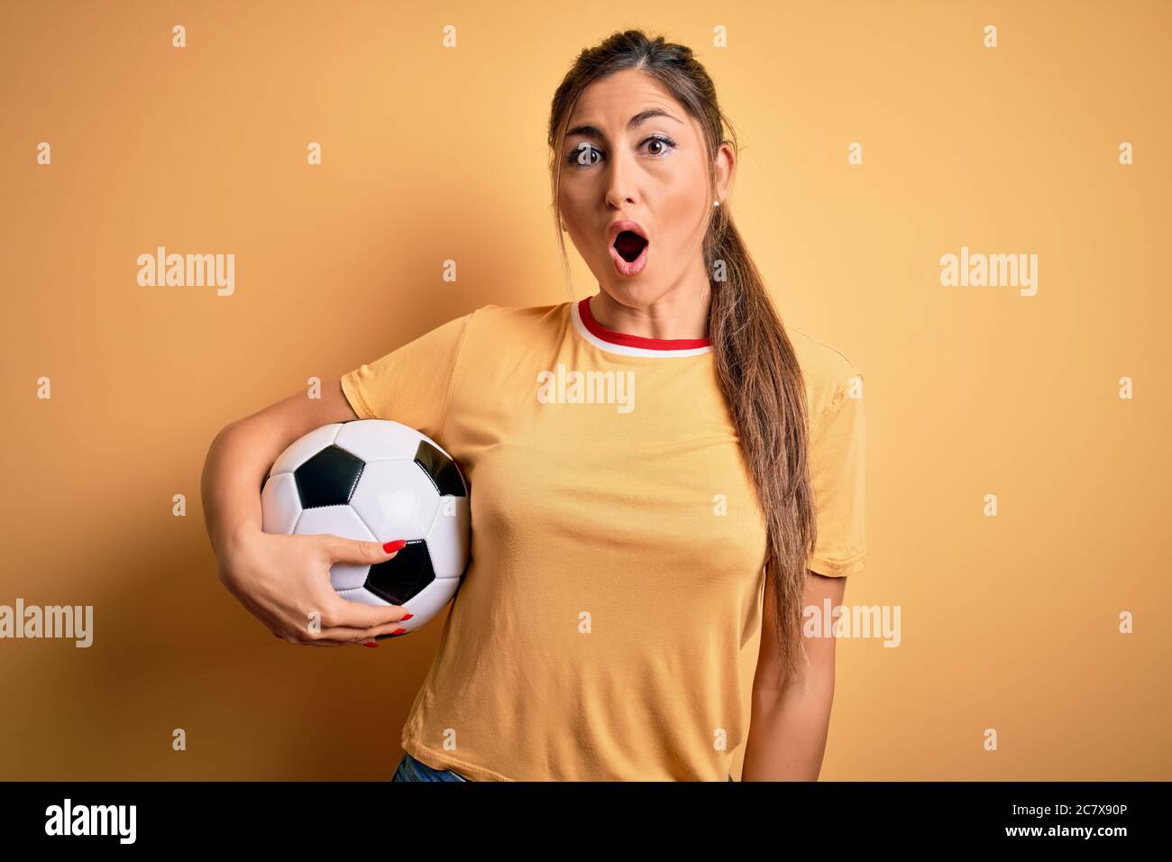 Beautiful brunette player woman playing soccer using football ball over ...