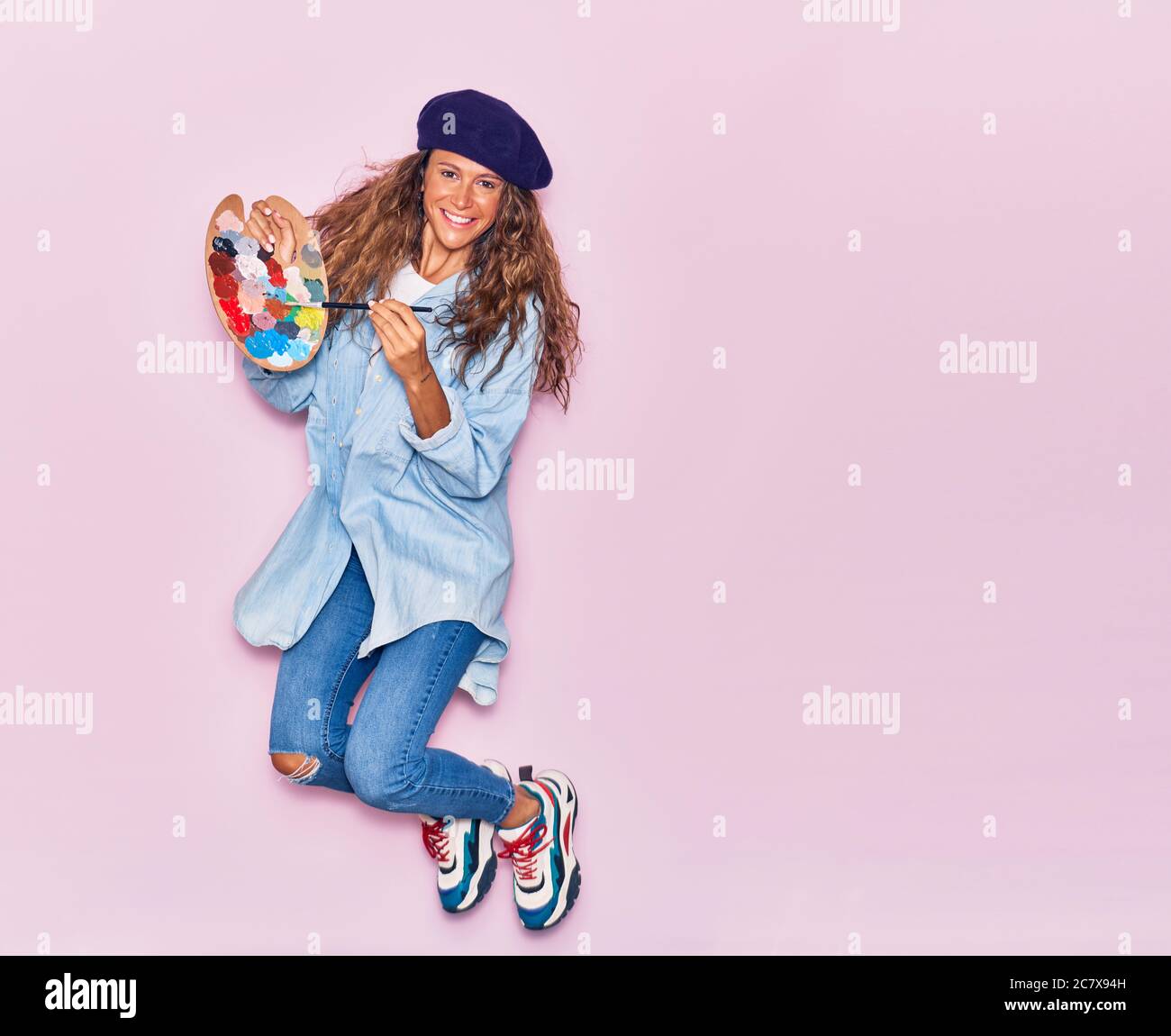 Young beautiful curly artist woman with tattoo wearing french beret ...