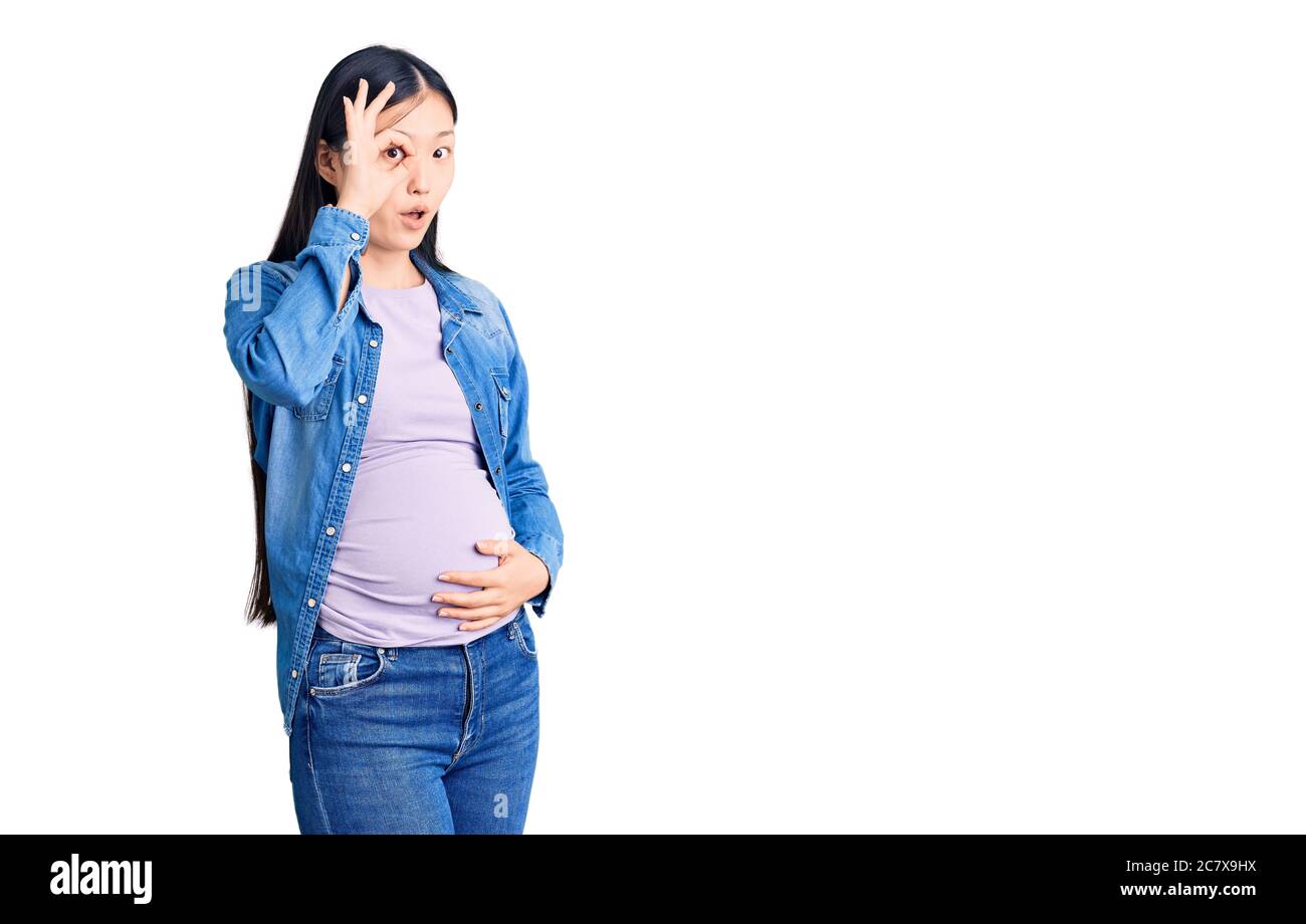 Young beautiful chinese woman pregnant expecting baby doing ok gesture ...