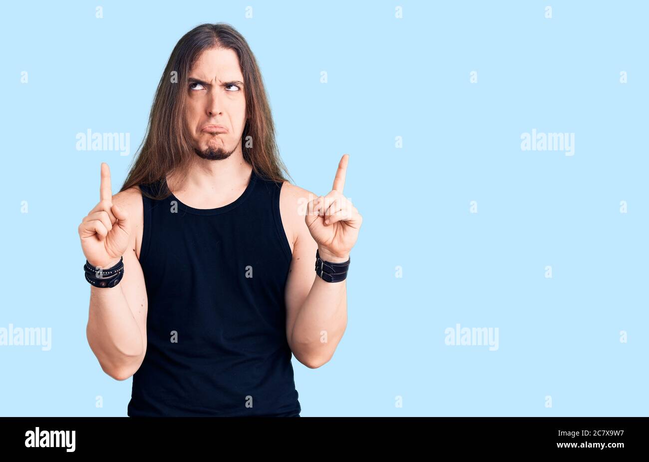 Young adult man with long hair wearing goth style with black clothes ...