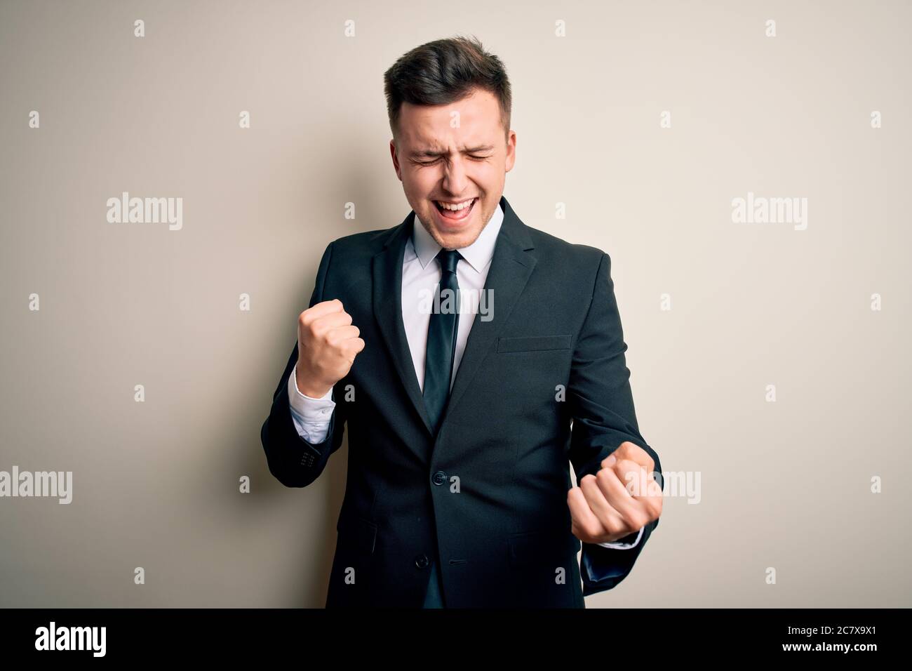 Young handsome business man wearing elegant suit and tie over isolated background celebrating ...