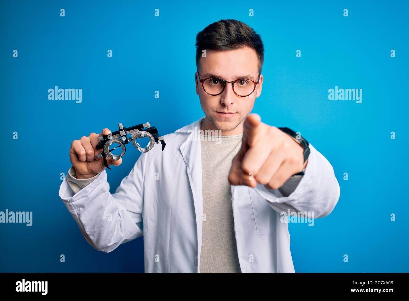 Young handsome professional optic man holding optometrical glasses over ...