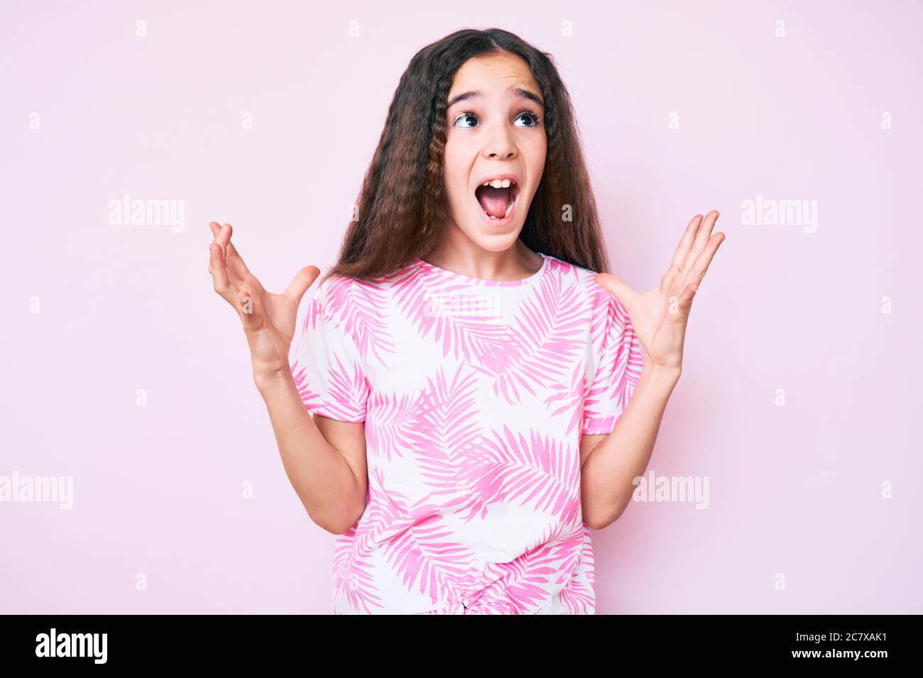 Cute hispanic child girl wearing casual clothes crazy and mad shouting ...