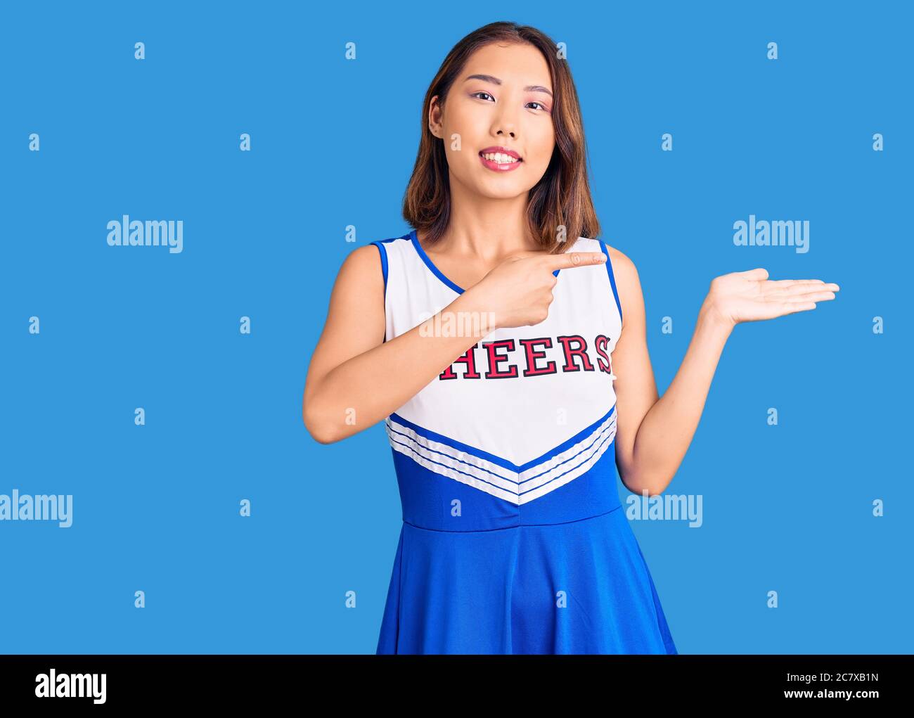 Young Beautiful Chinese Girl Wearing Cheerleader Uniform Amazed And