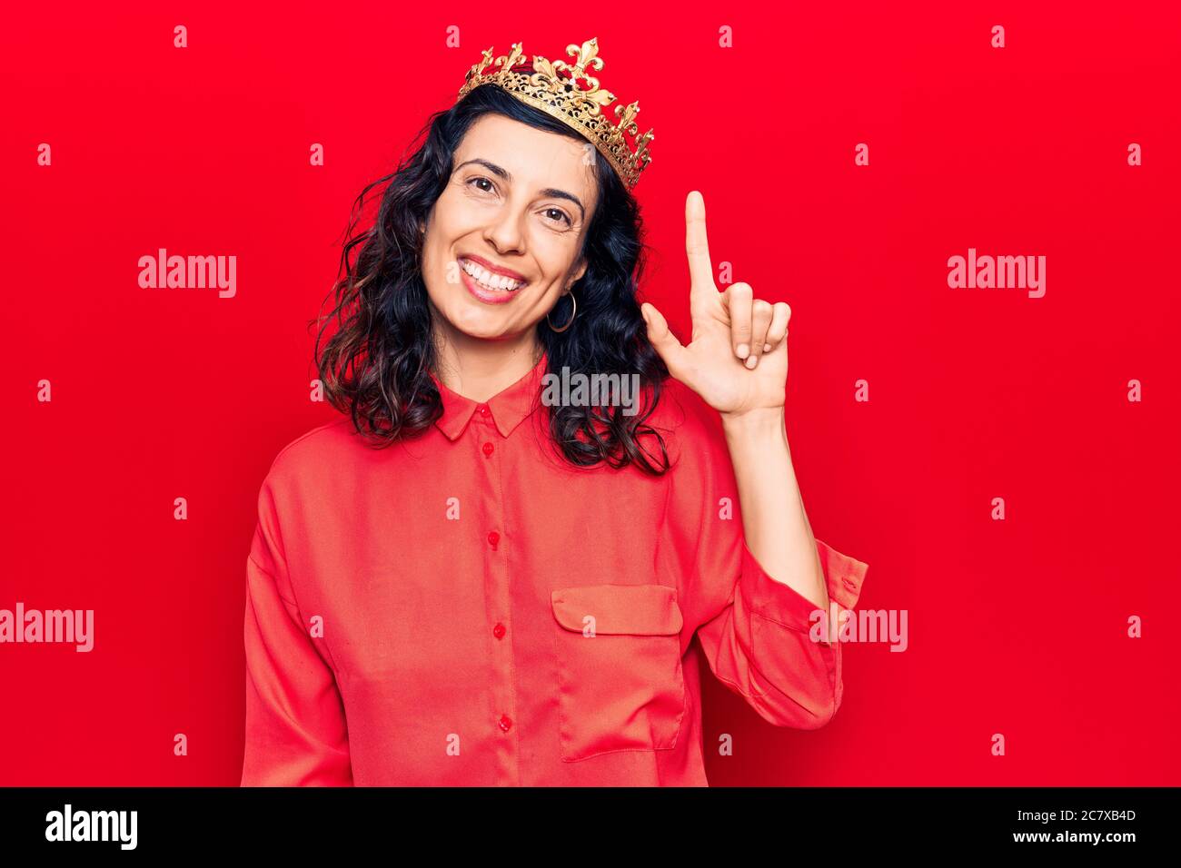 Young beautiful hispanic woman wearing princess crown smiling with an ...