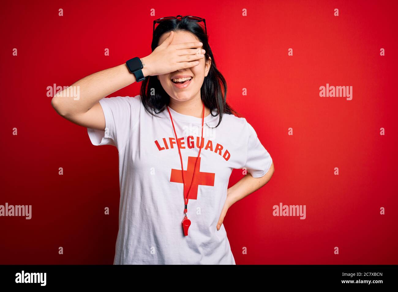 Young lifeguard woman wearing secury guard equipent over red background ...