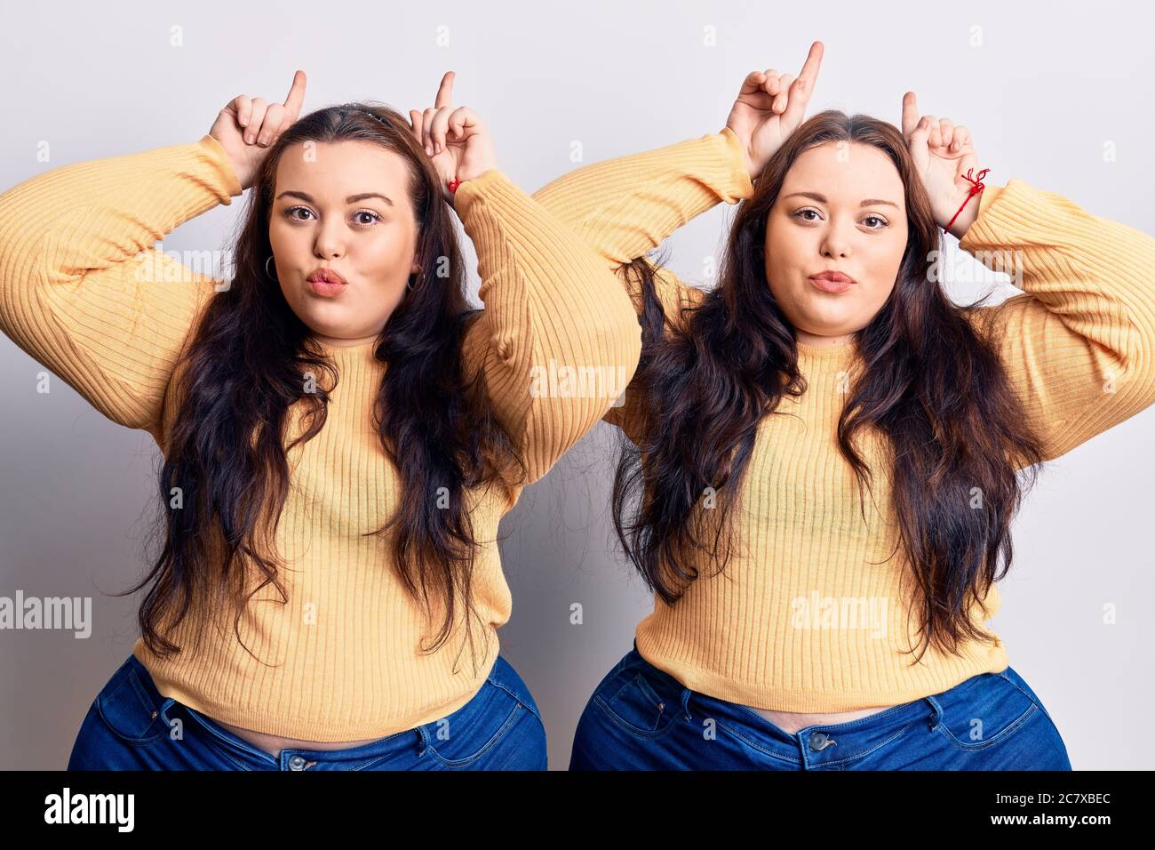 Young plus size twins wearing casual clothes doing funny gesture with ...