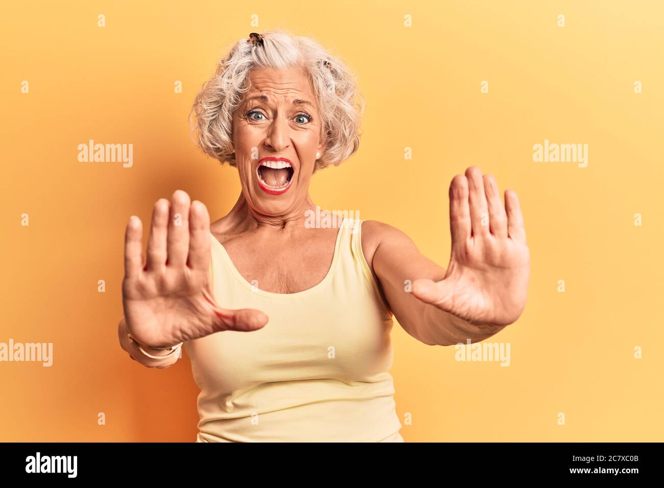 Senior grey-haired woman wearing casual clothes afraid and terrified ...