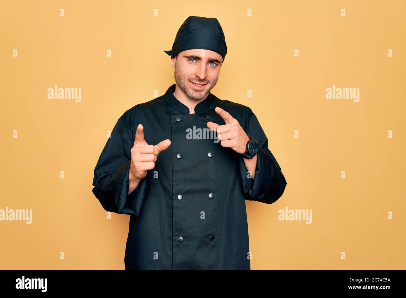 Young handsome cooker man with blue eyes wearing uniform and hat over ...