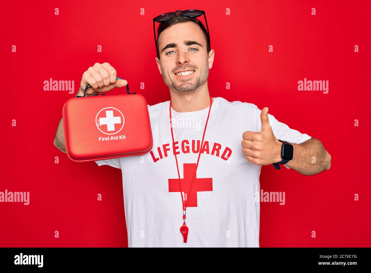 Young handsome lifeguard man wearing t-shirt with red cross and whistle ...