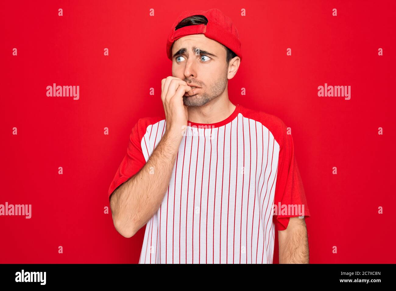 Young handsome sporty man with blue eyes wearing striped baseball t ...