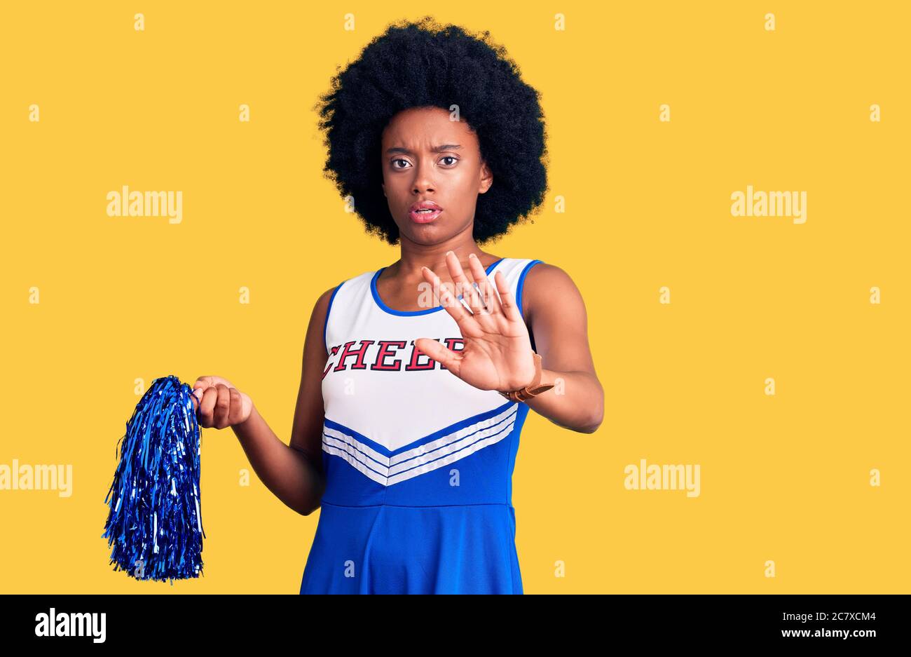 Young african american woman wearing cheerleader uniform holding pompom ...