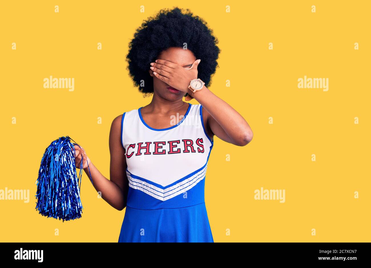 Young african american woman wearing cheerleader uniform holding pompom ...