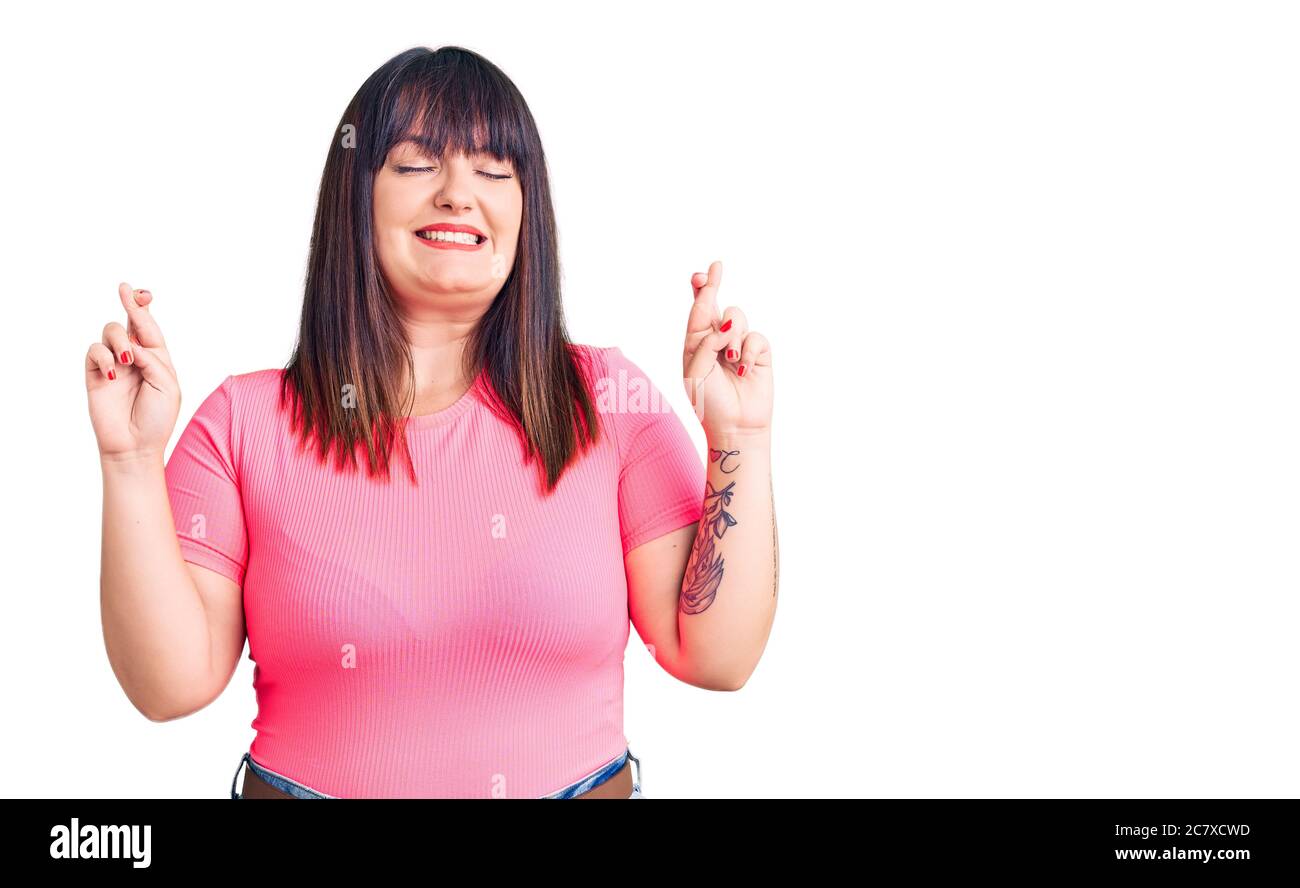 Young plus size woman wearing casual clothes gesturing finger crossed ...