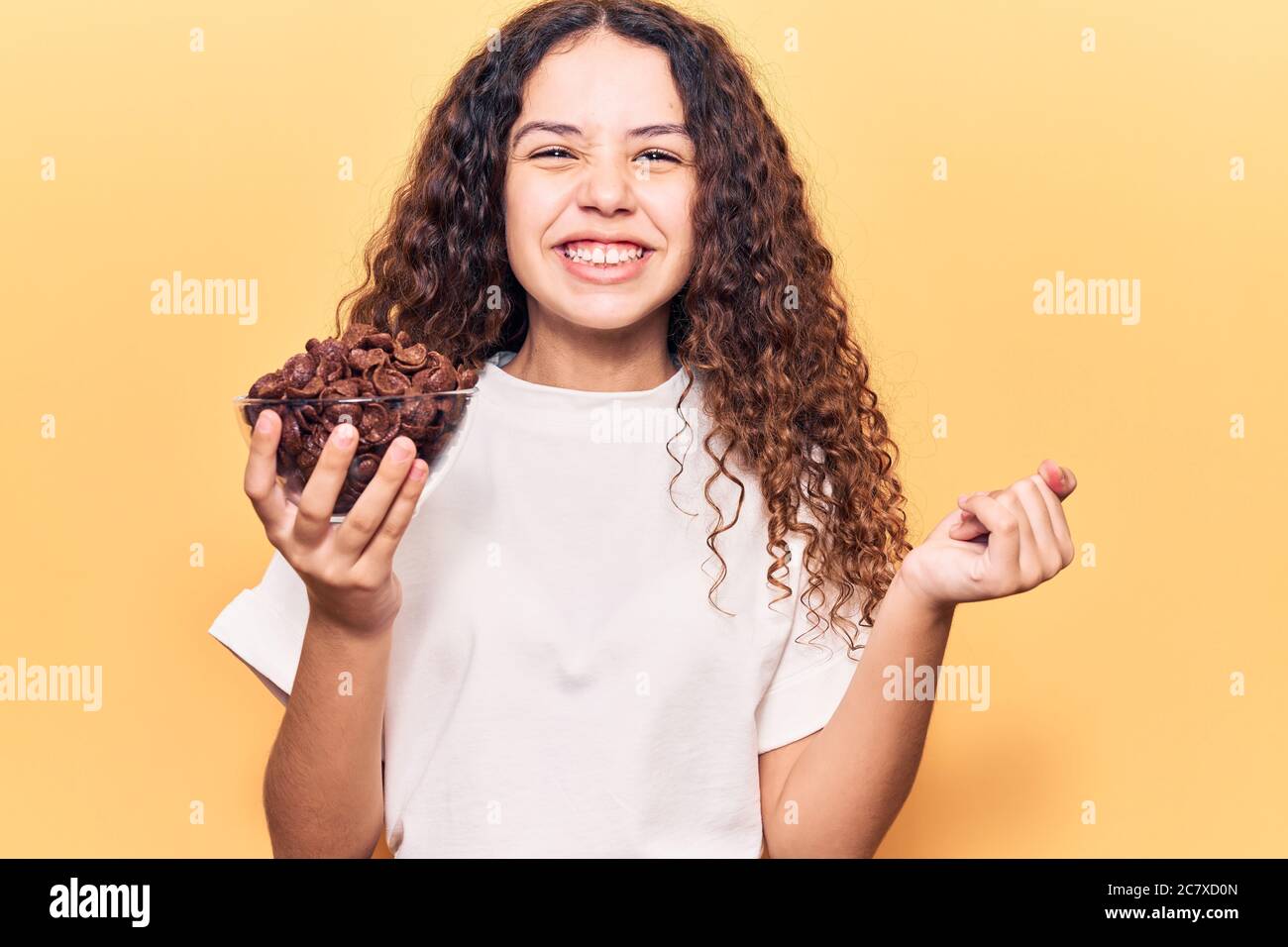 Beautiful kid girl with curly hair holding chocolate cereals screaming ...