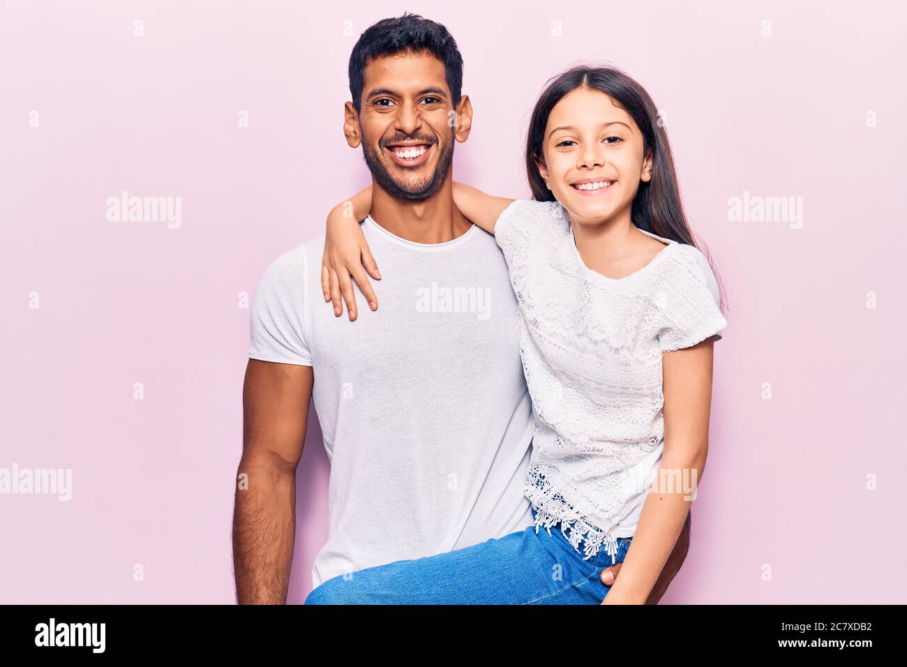 Latin father and daughter wearing casual clothes looking positive and ...