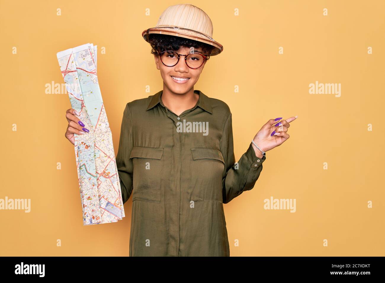 Beautiful african american explorer woman wearing hat holding city map ...