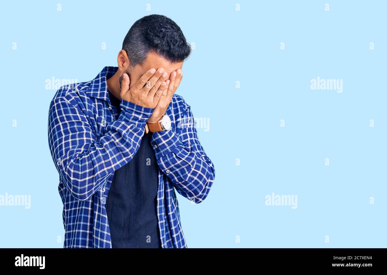 Young hispanic man wearing casual clothes with sad expression covering ...