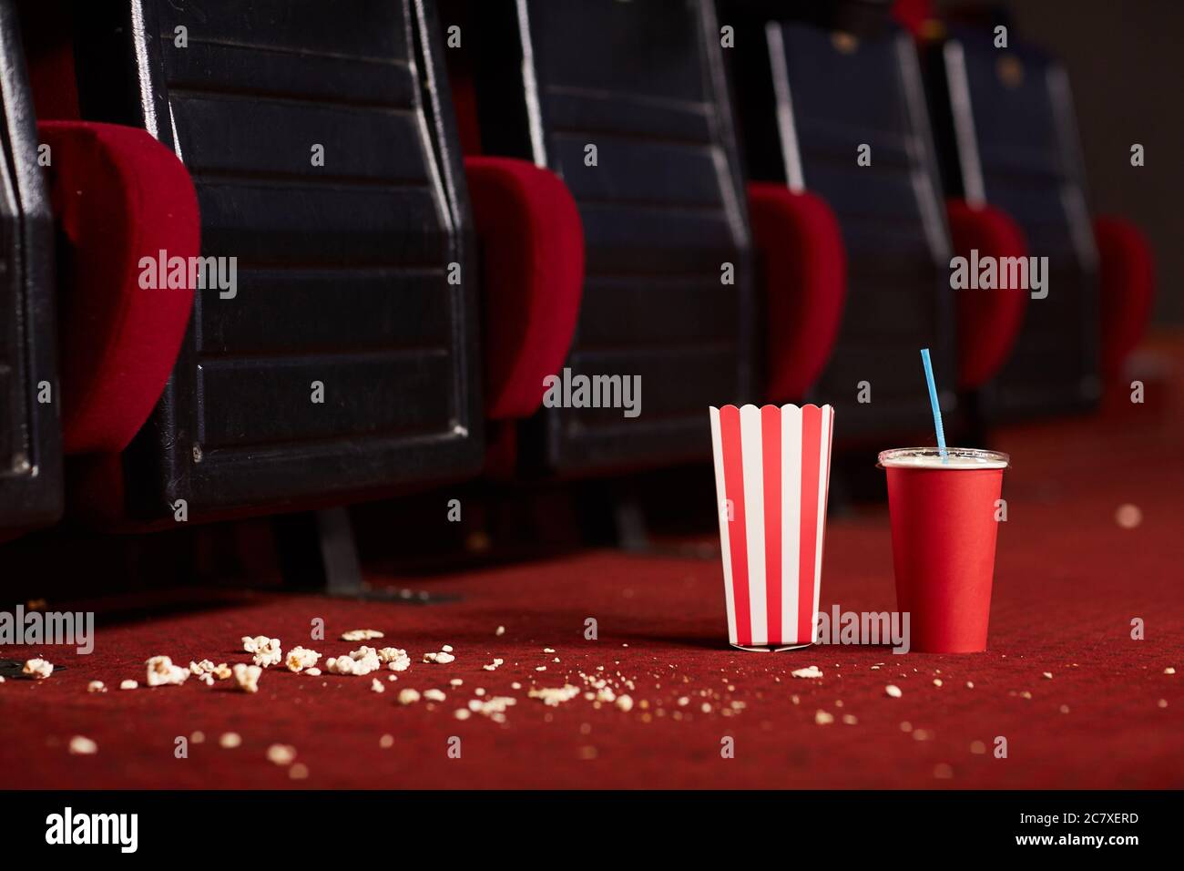 Close up background image of soda cup and popcorn on messy red floor in ...