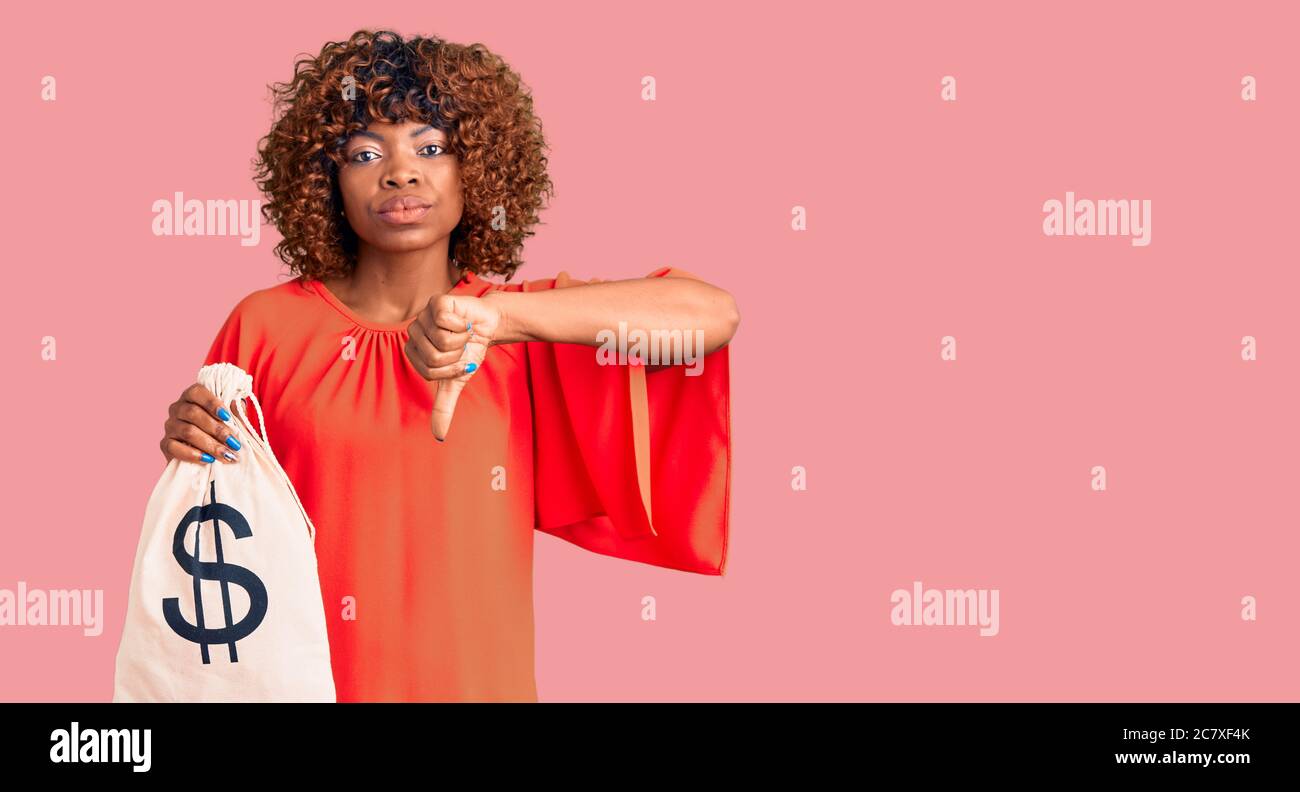 Young african american woman holding money bag with dollar symbol with ...