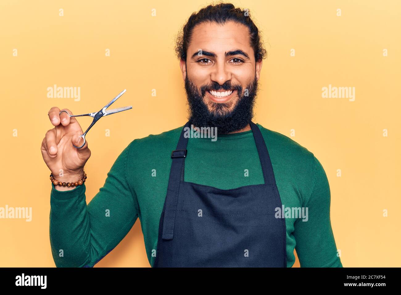 Young arab man wearing barber apron looking positive and happy standing ...