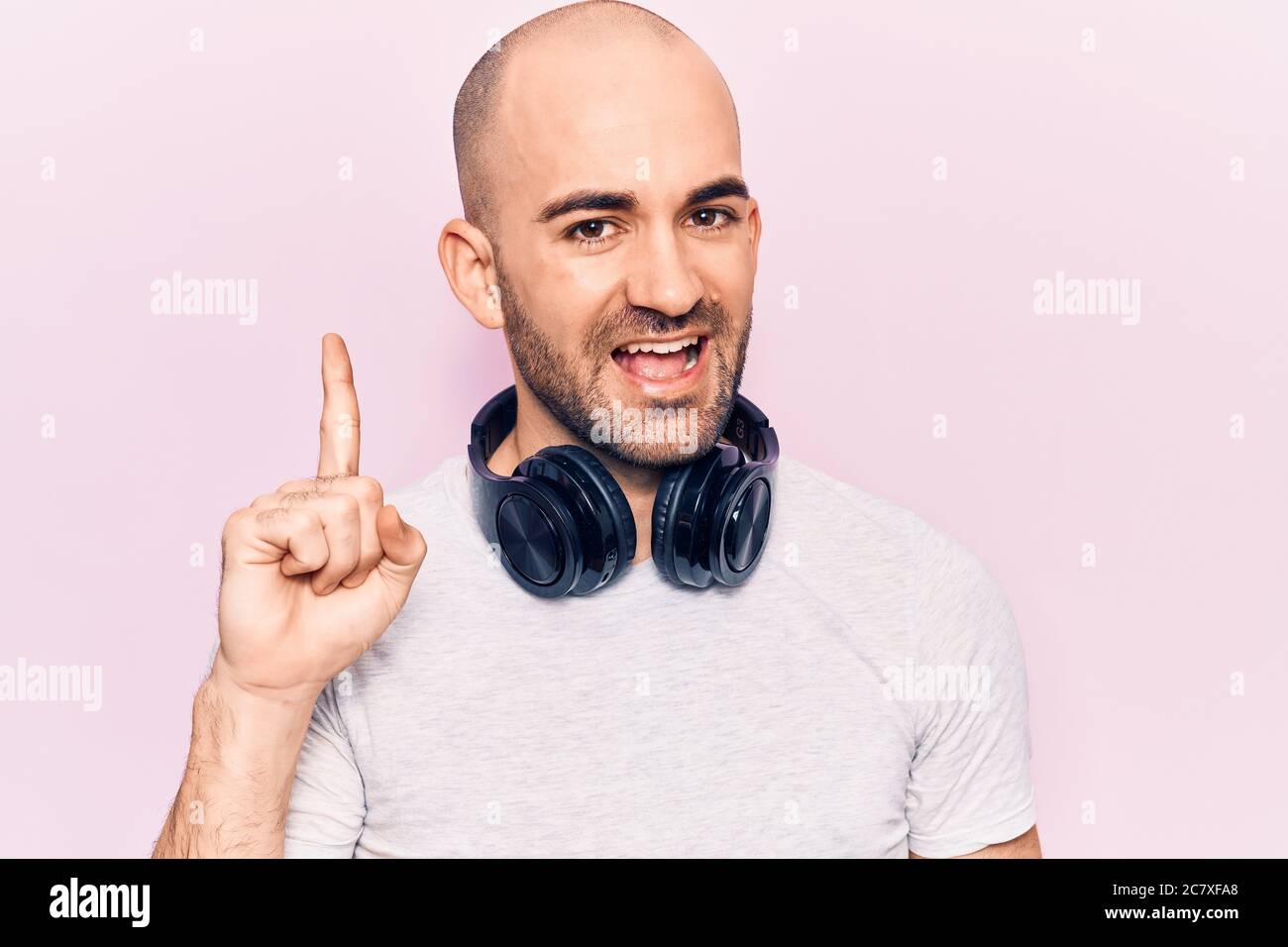 Young handsome bald man listening to music using headphones smiling ...