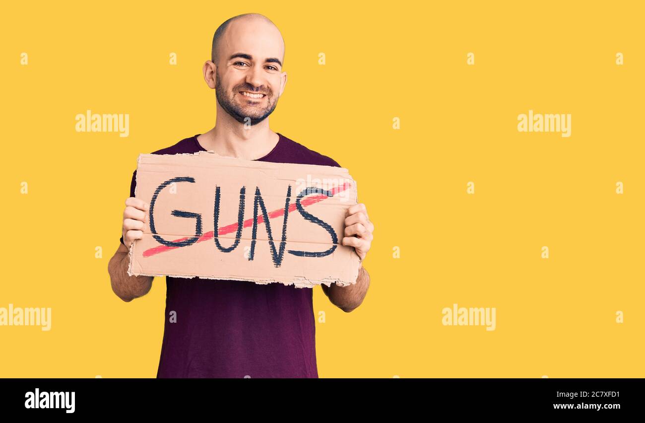 Young handsome man holding prohibited guns banner looking positive and ...