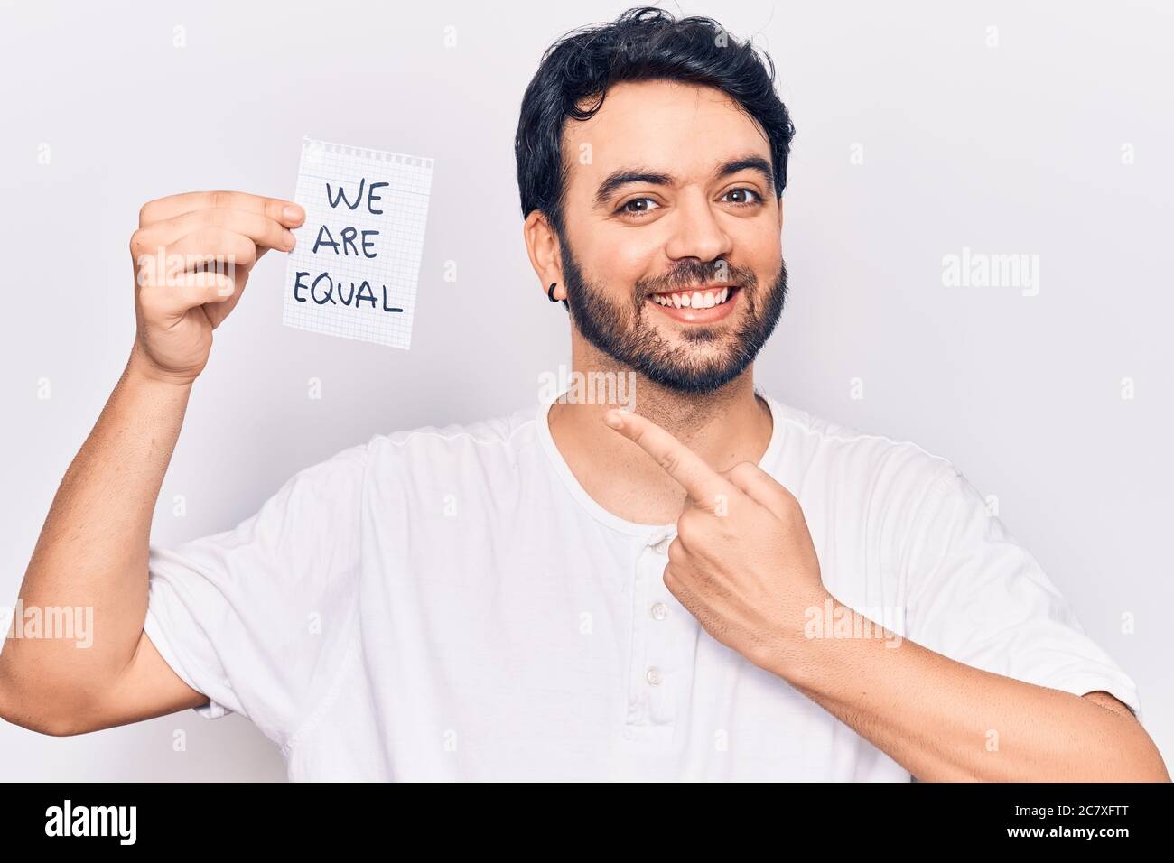 Young hispanic man holding we are equal paper smiling happy pointing ...