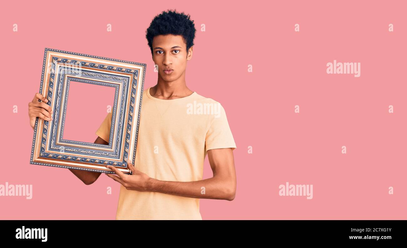 Young african american man holding empty frame thinking attitude and ...