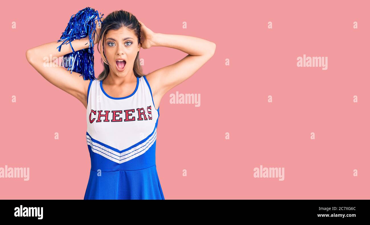 Young beautiful woman wearing cheerleader uniform crazy and scared with ...