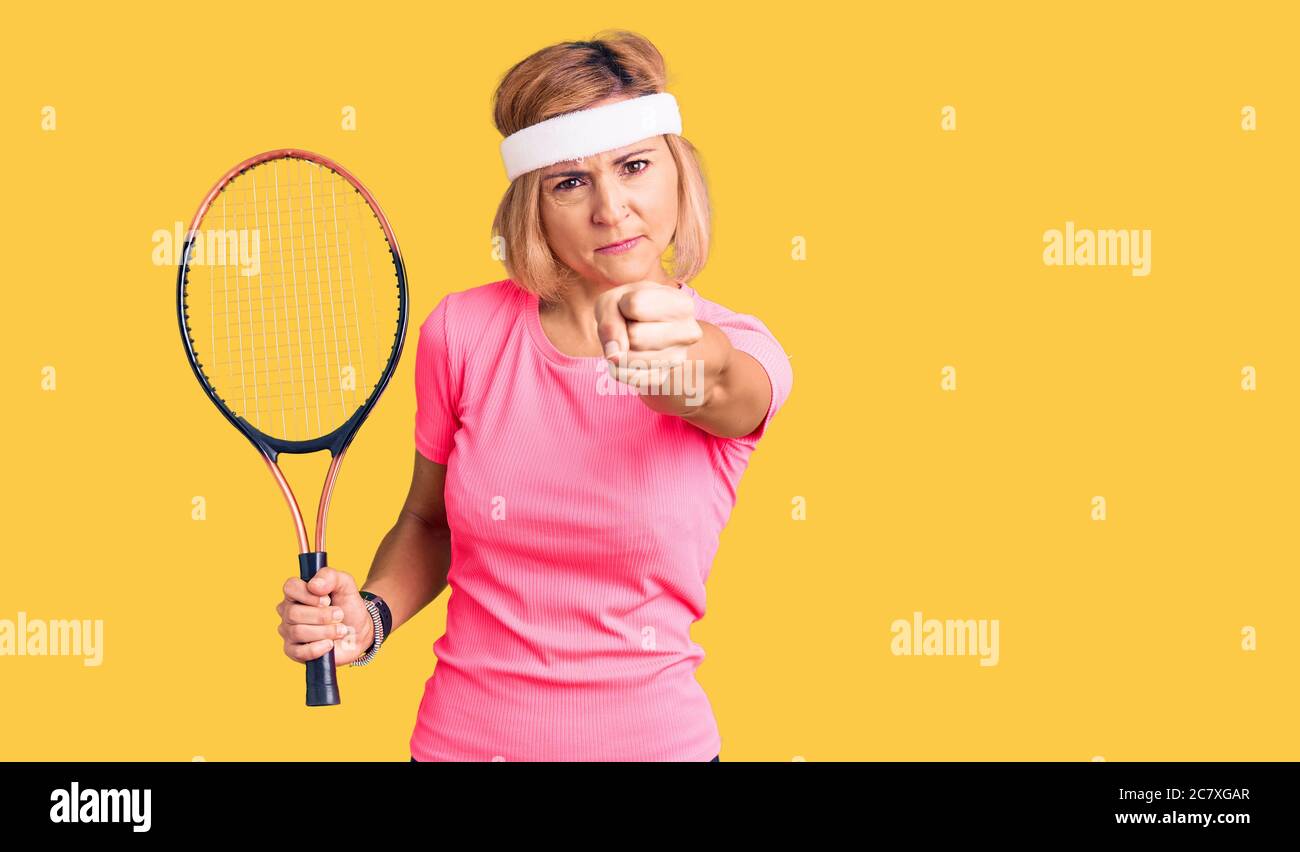 Young blonde woman playing tennis holding racket annoyed and frustrated ...