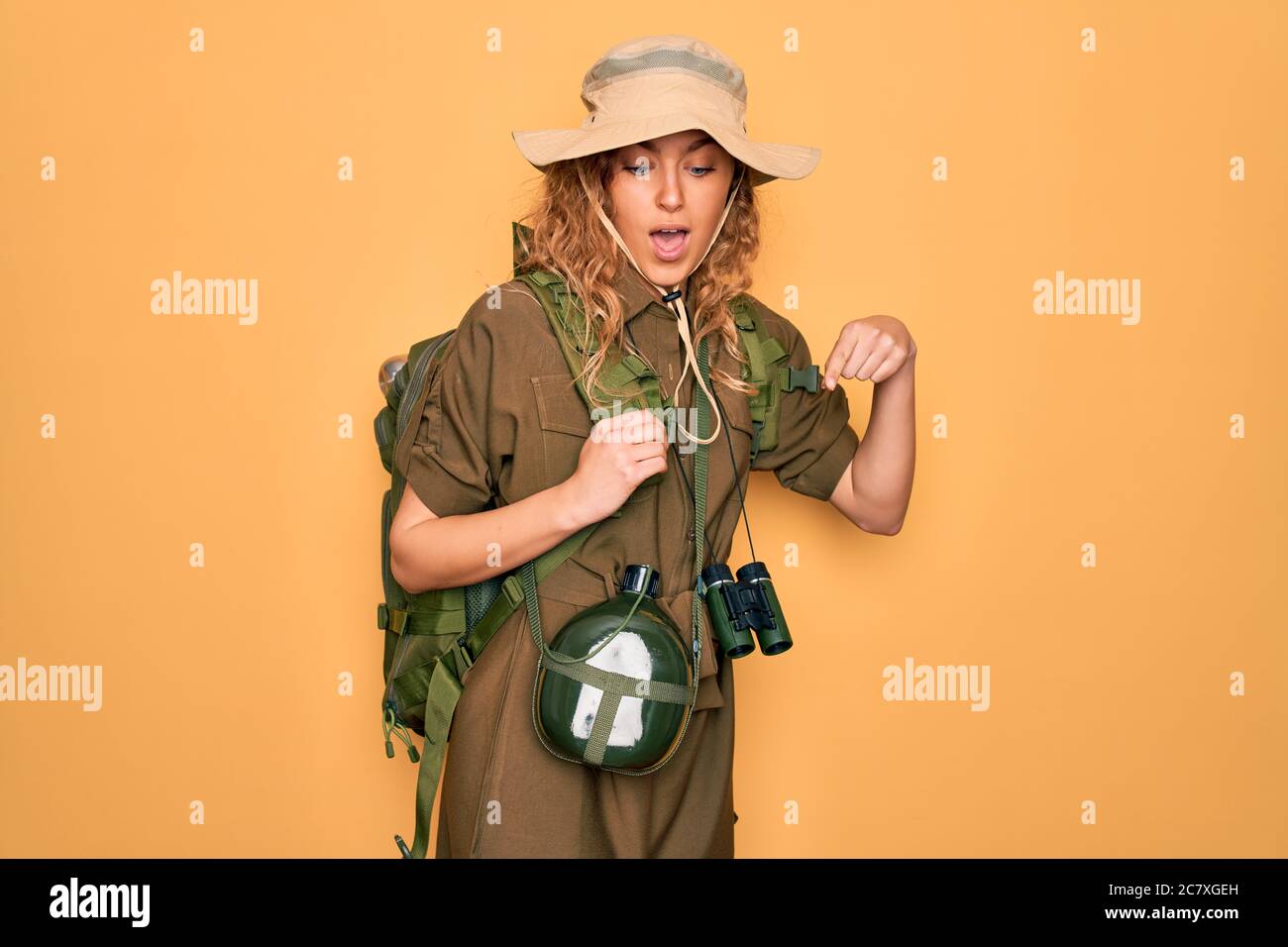 Young blonde explorer woman with blue eyes hiking wearing backpack and ...