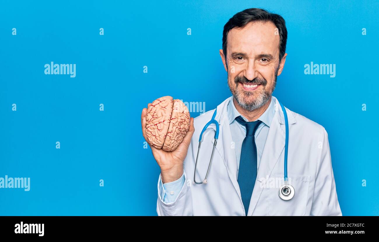 Middle age handsome doctor man wearing coat and stethoscope holding ...